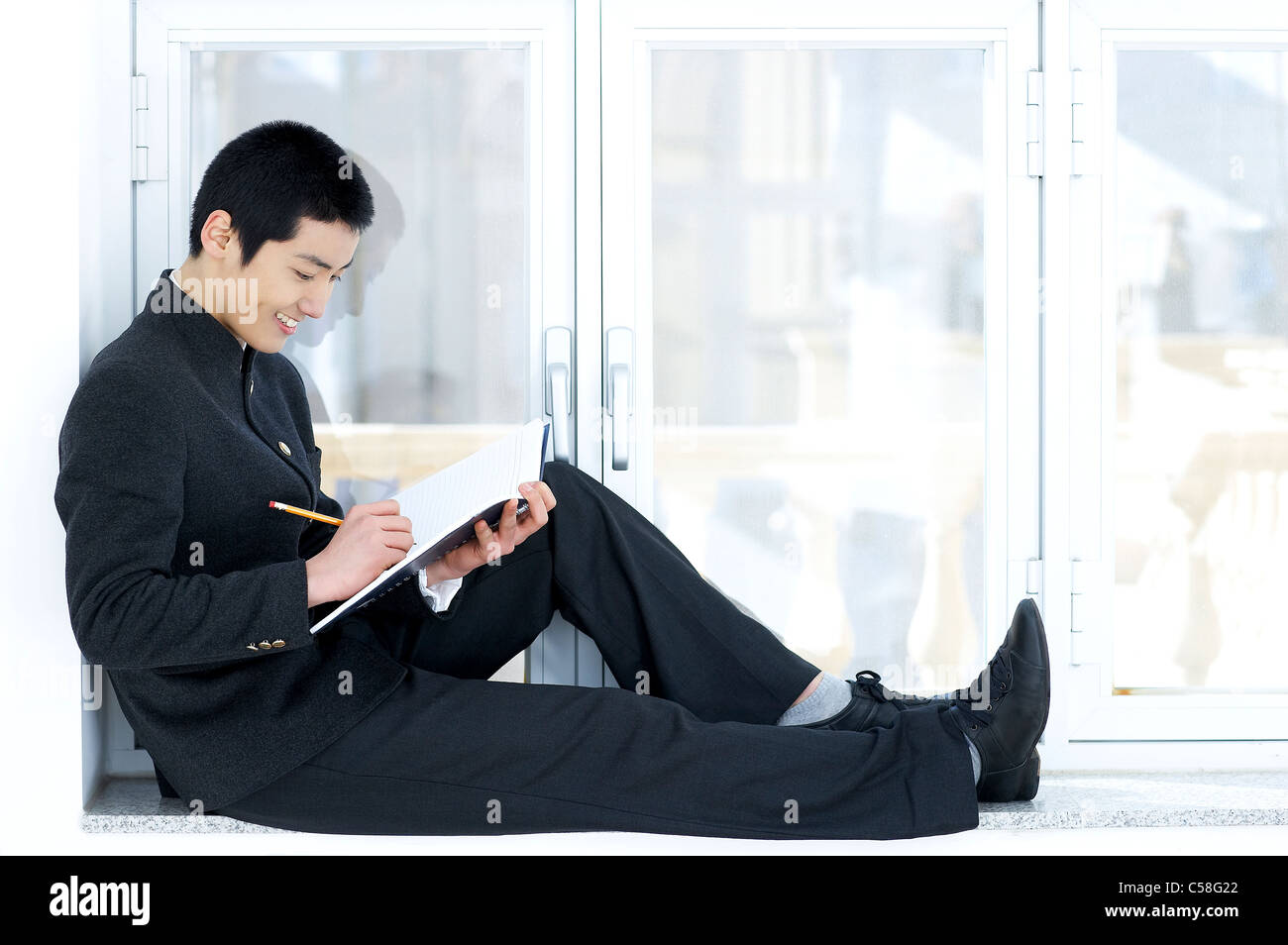 Side view of teenage boy writing in book Stock Photo - Alamy