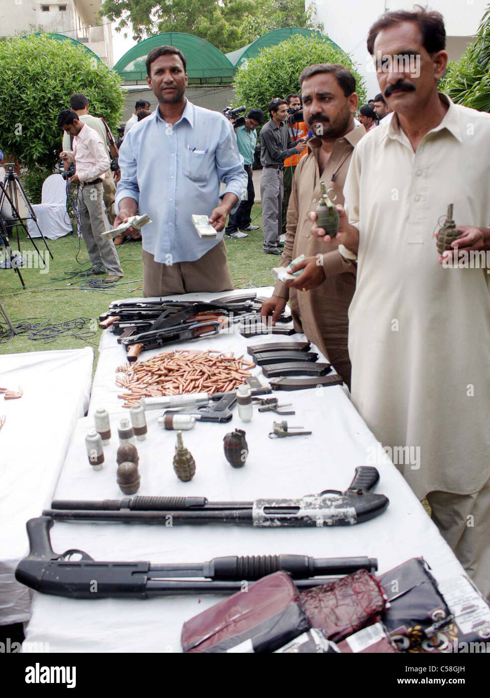 Plain-cloth policemen show seized weapons, bullets, hand grenades, cash ...