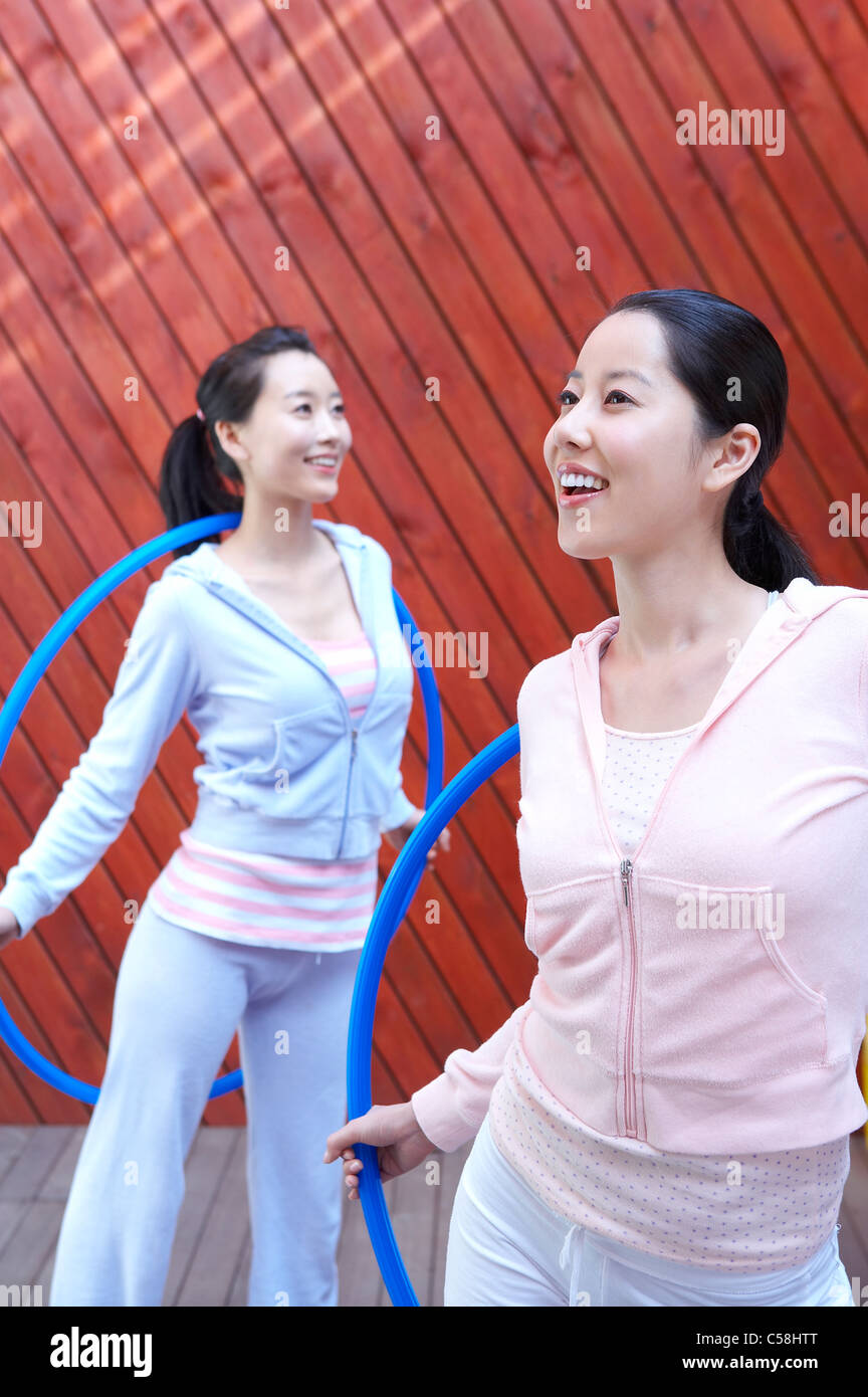 Side view of young women holding hula hoop Stock Photo - Alamy