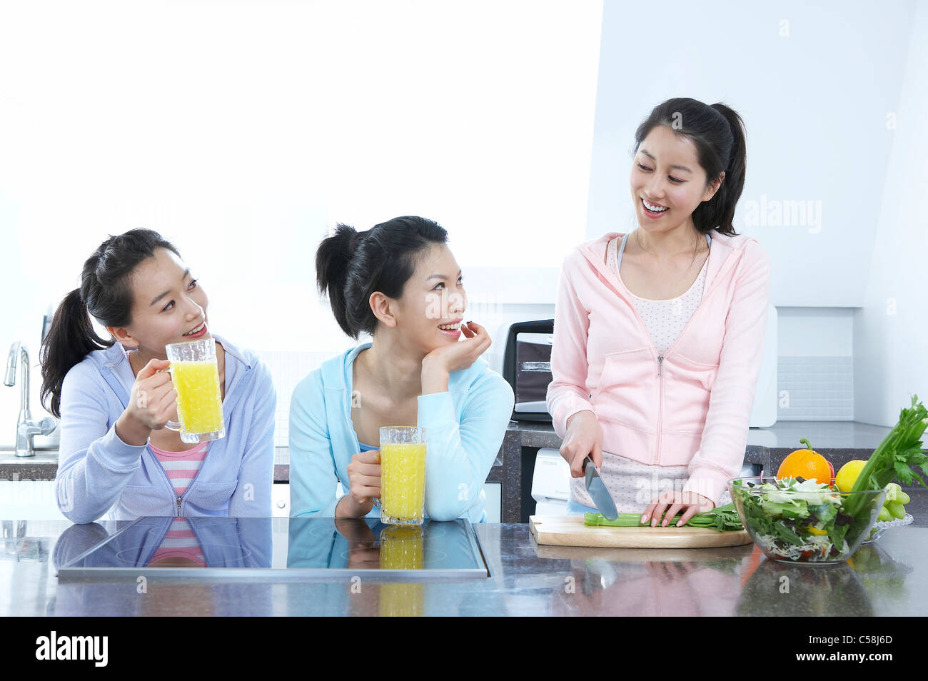 Young women sitting on dining table Stock Photo - Alamy