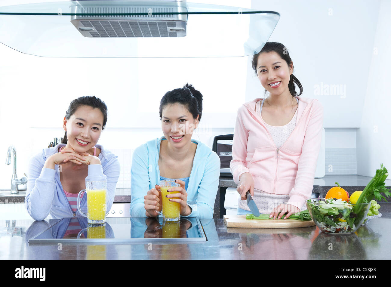 Portrait of young women sitting on dining table Stock Photo - Alamy