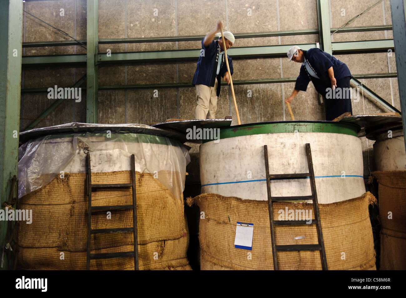 Two men are stirring mirin, a sweet rice wine Stock Photo - Alamy
