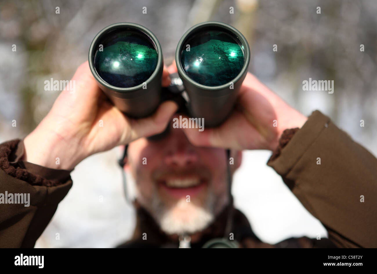 Smiling man looking through binoculars Stock Photo - Alamy