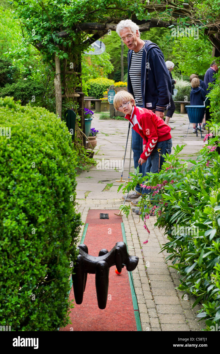 Grandpa and grandson playing minigolf Stock Photo - Alamy
