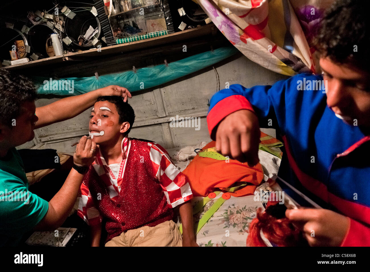 A Colombian boy has a color applied to his face to set his clown makeup ...