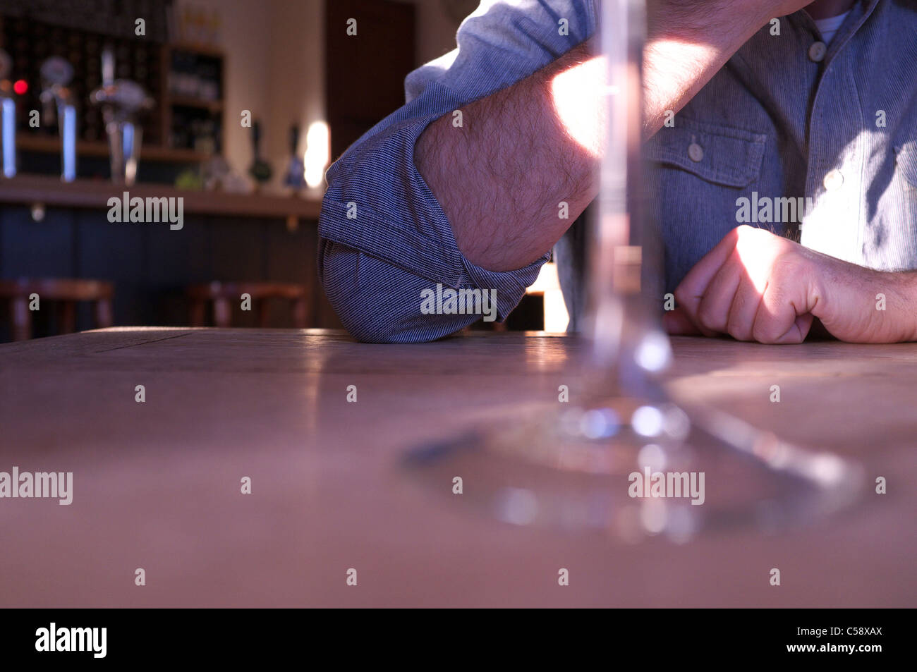 Man leaning on table in pub with wine glass Stock Photo - Alamy