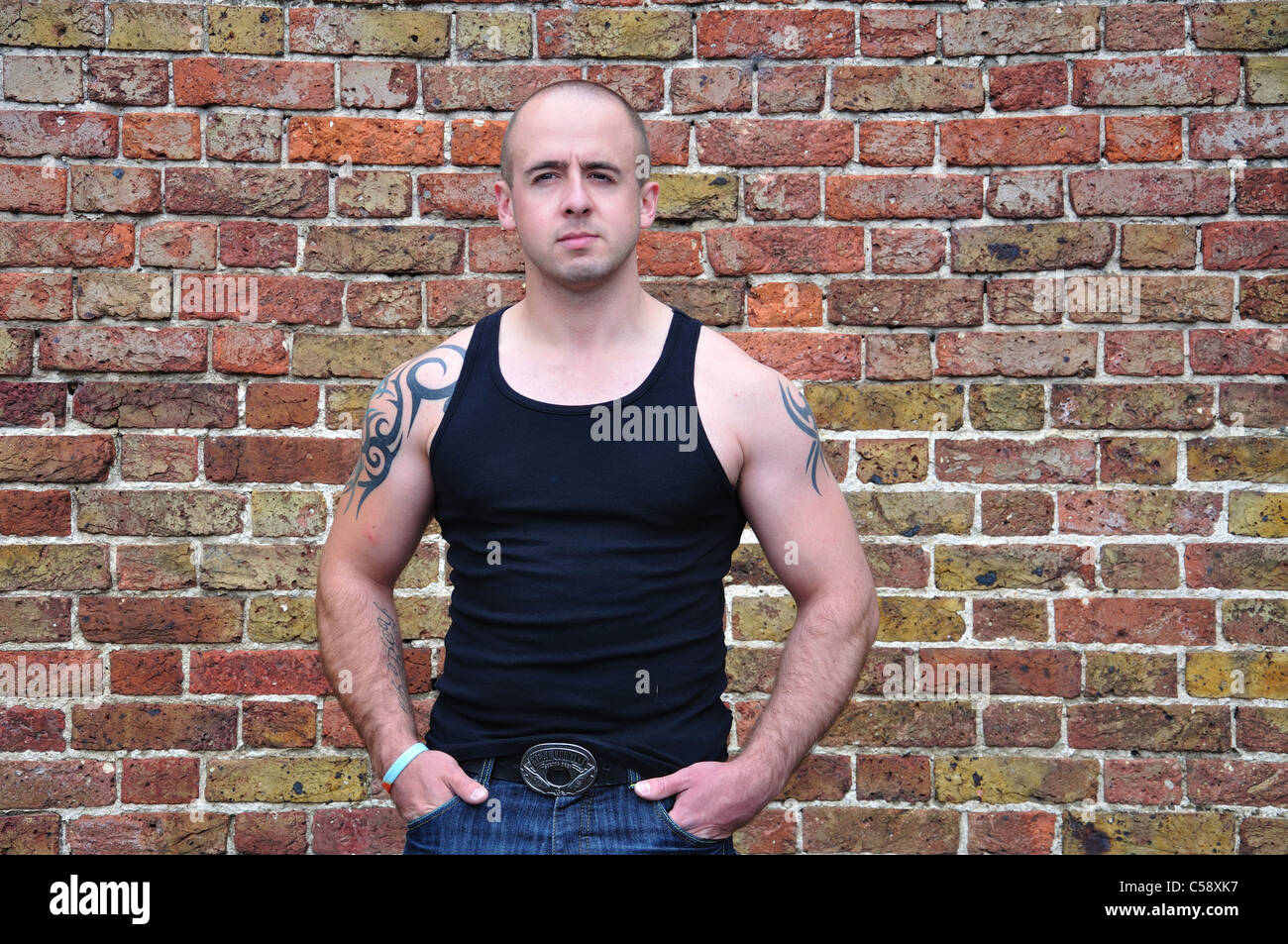 Young male model posing by brick wall, Old Shepperton Village, Surrey ...