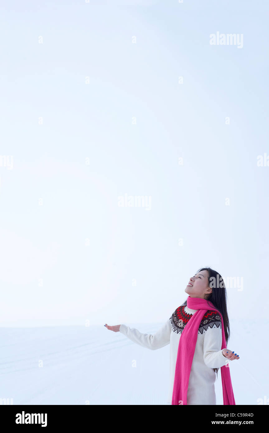 Side view of young woman standing with arms outstretched on snowcapped ...