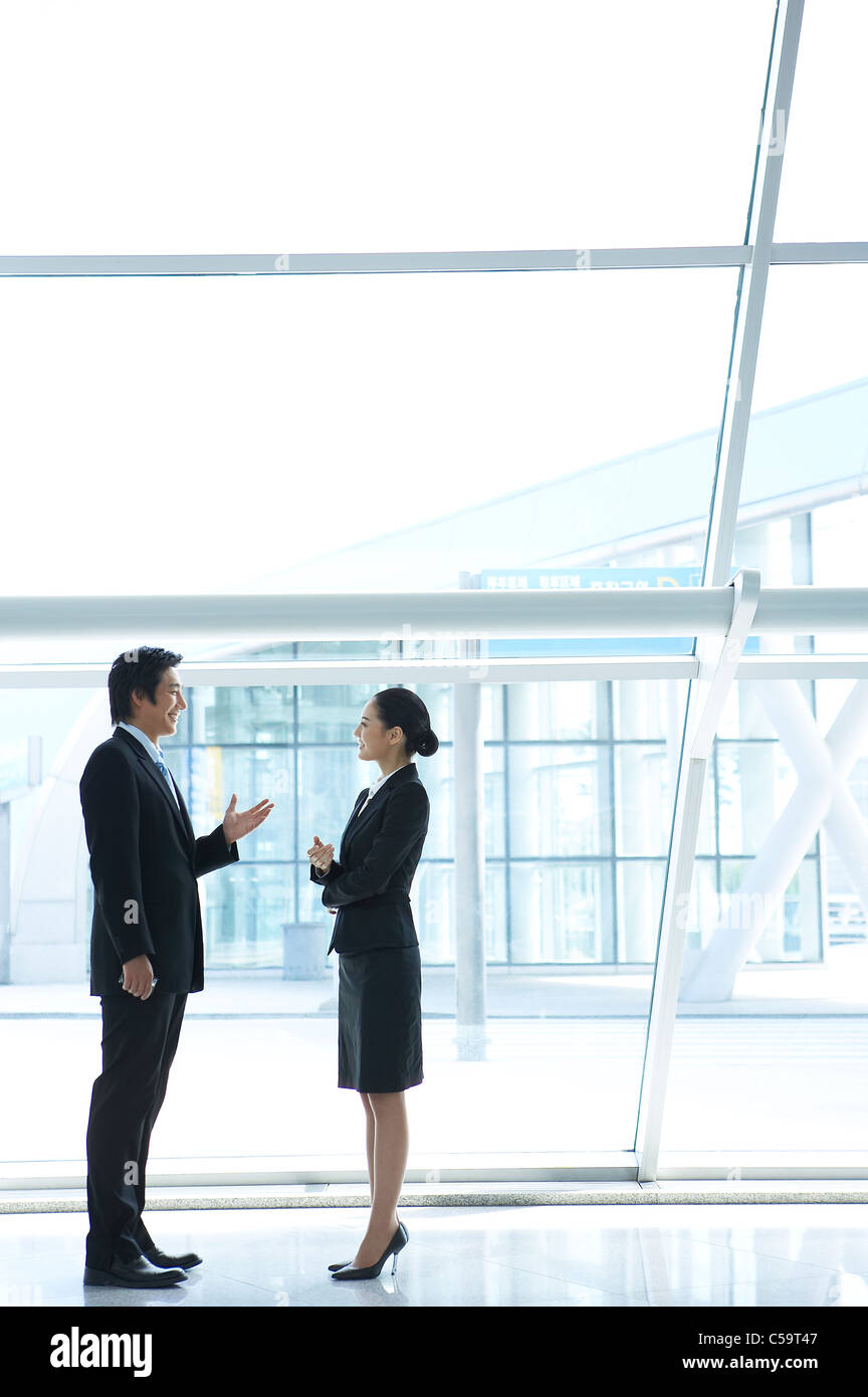 Side view of businessman and businesswoman talking Stock Photo - Alamy