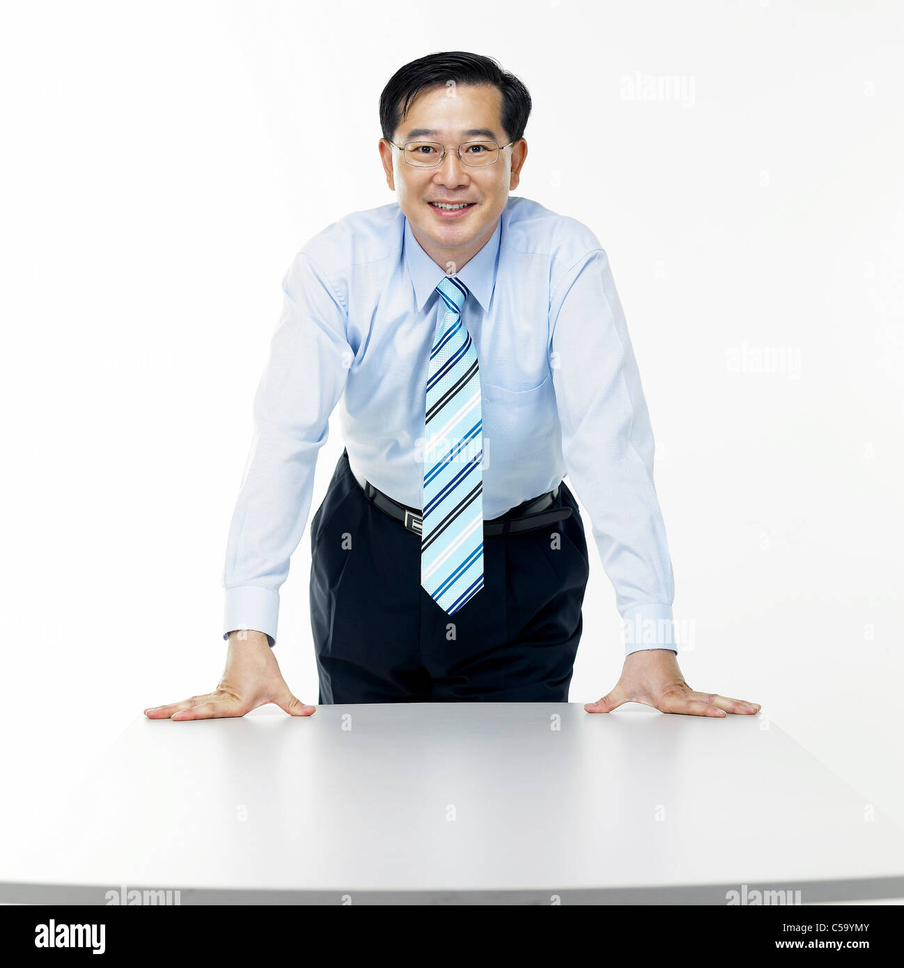Portrait of businessman standing by table Stock Photo - Alamy