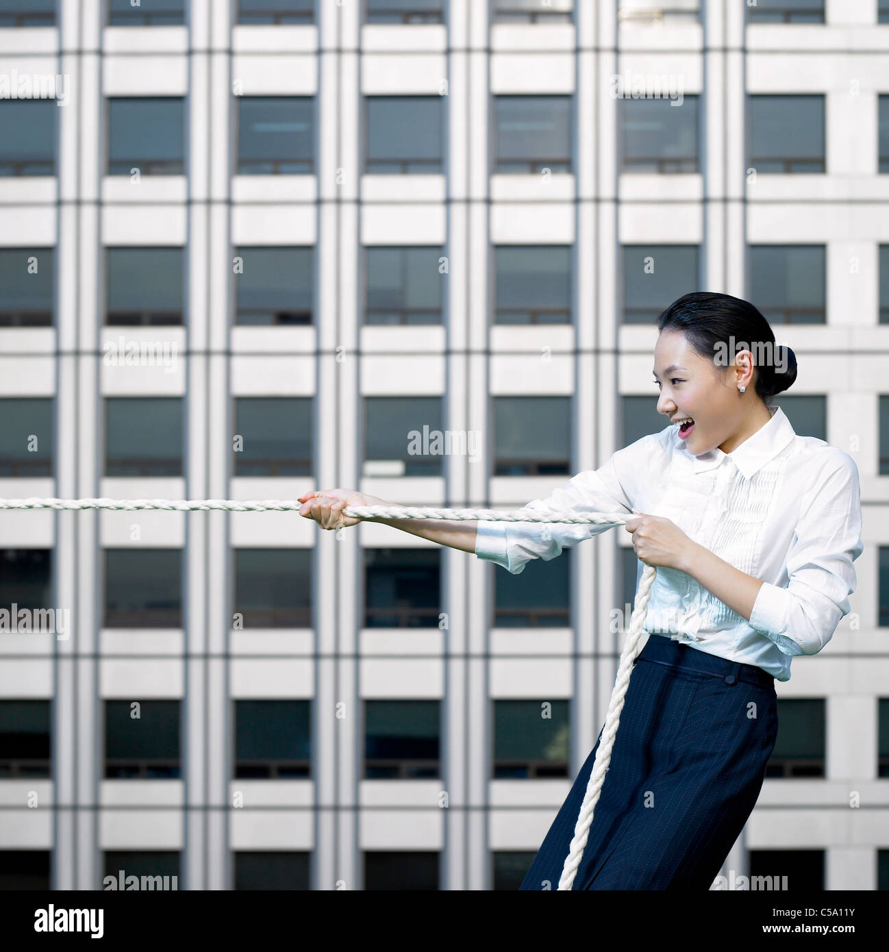 Side view of businesswoman pulling rope Stock Photo - Alamy