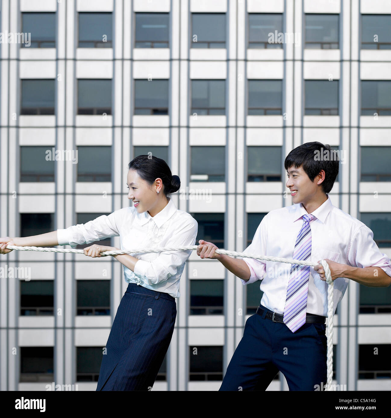 Side view of businesspeople pulling rope Stock Photo - Alamy