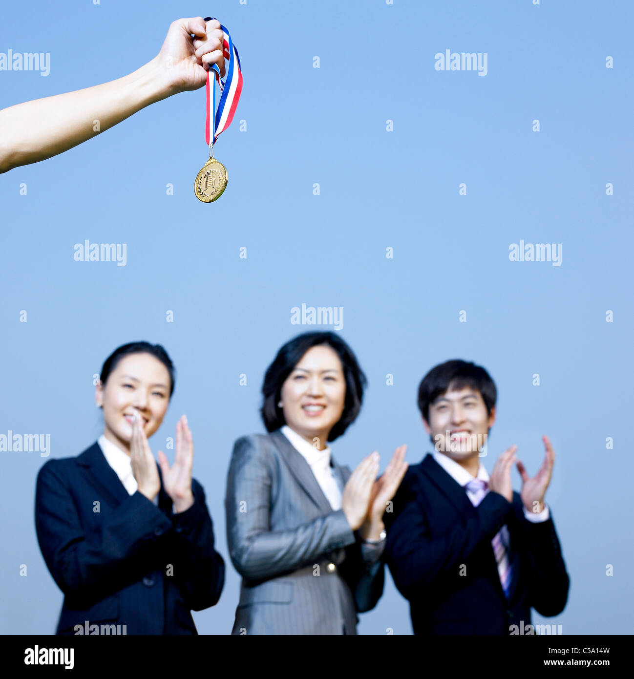 Person holding medal with businesspeople standing Stock Photo - Alamy