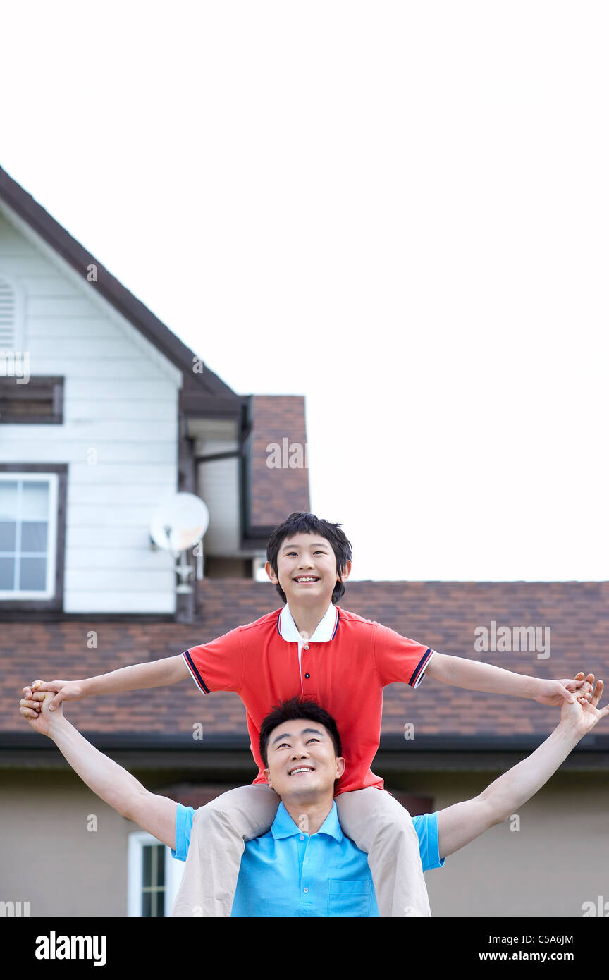 Low angle view of son sitting on father's shoulders Stock Photo - Alamy