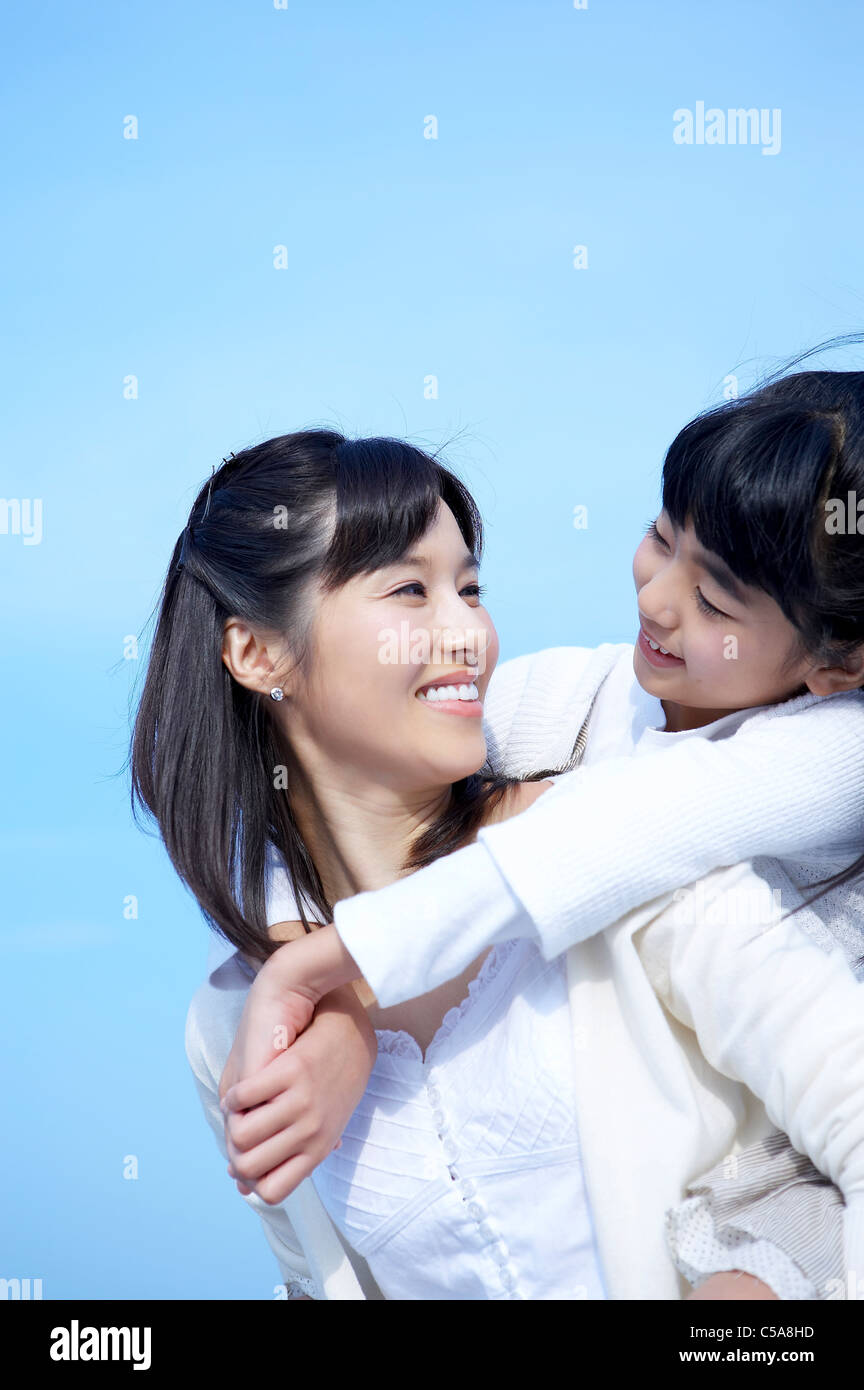 Side view of mother carrying daughter on back Stock Photo - Alamy