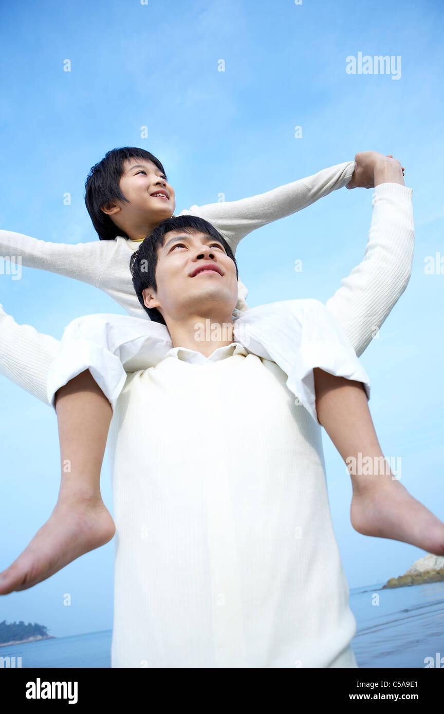 Low angle view of son sitting on father's shoulders Stock Photo - Alamy