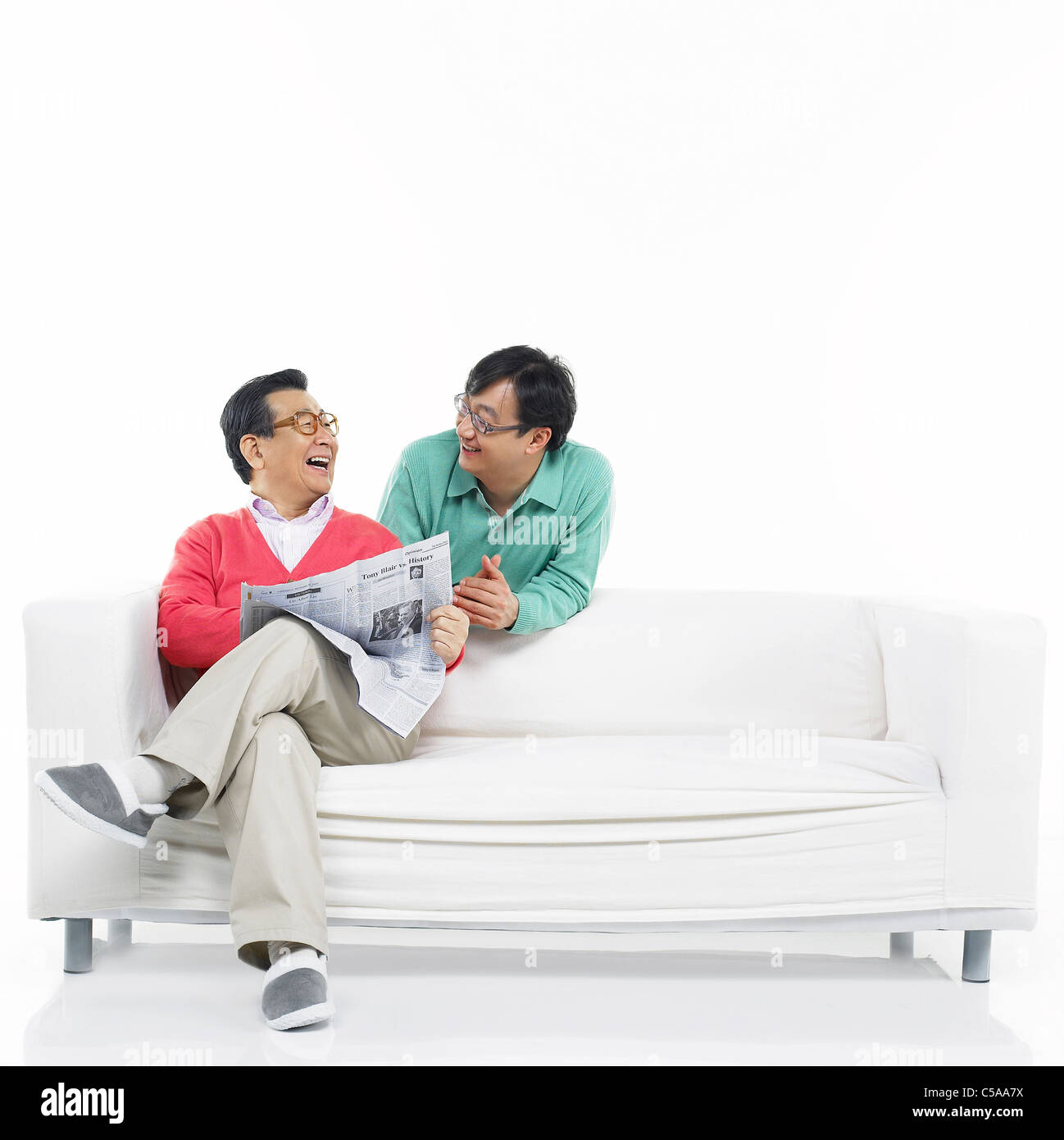 Father and son smiling, while reading newspaper Stock Photo - Alamy