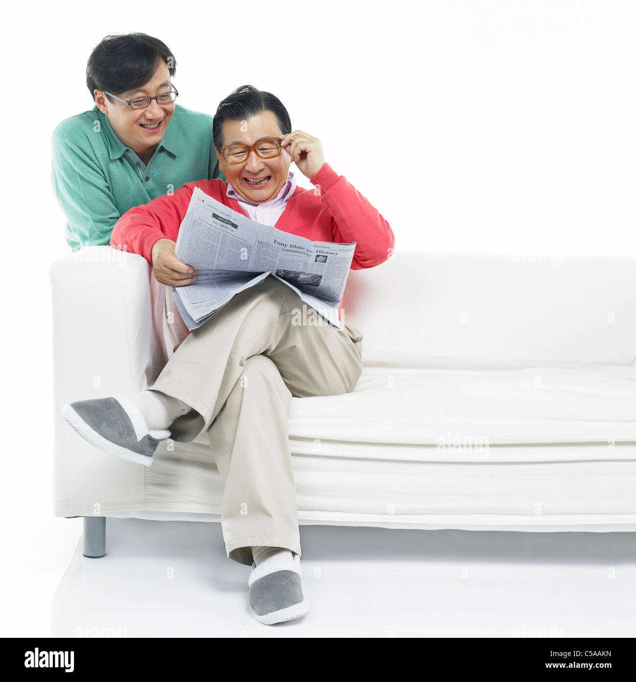 Father and son smiling, while reading newspaper Stock Photo - Alamy