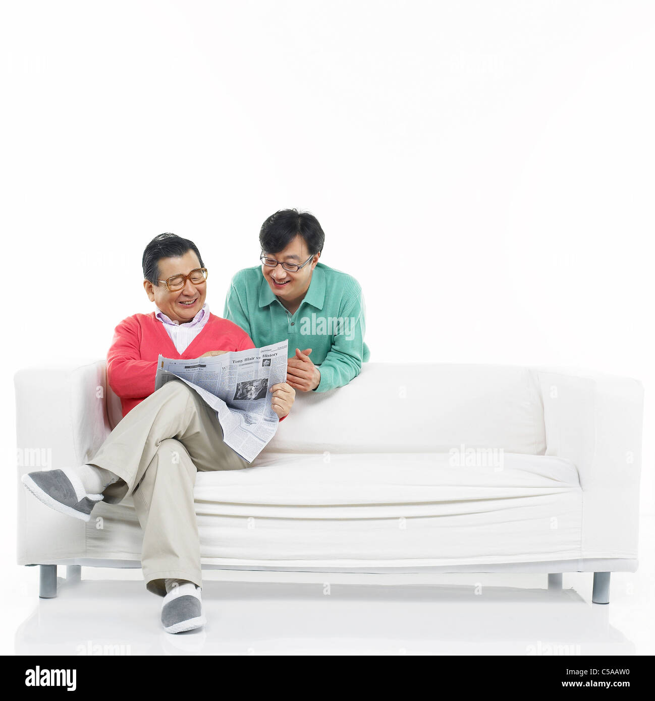 Father and son smiling, while reading newspaper Stock Photo - Alamy