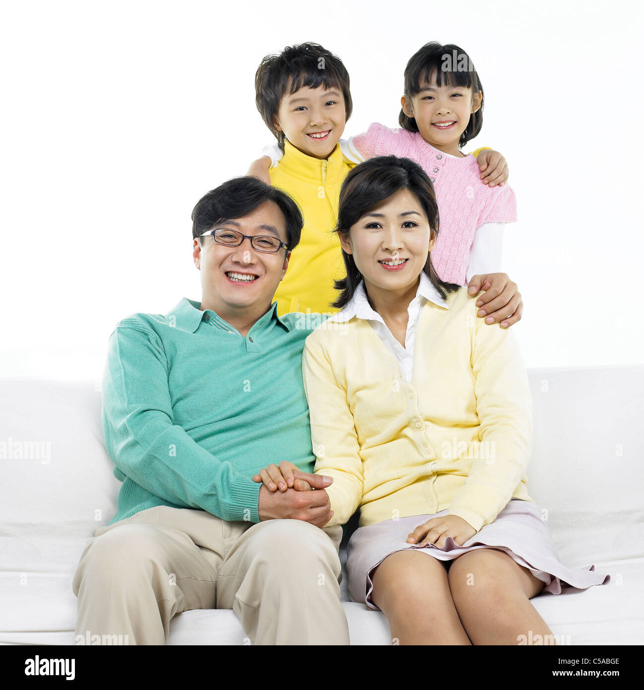 Parents sitting with children on sofa Stock Photo - Alamy