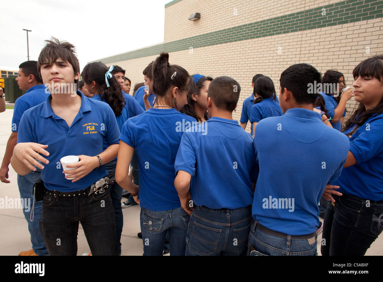 Group of male and female students wearing school uniform gather outside ...