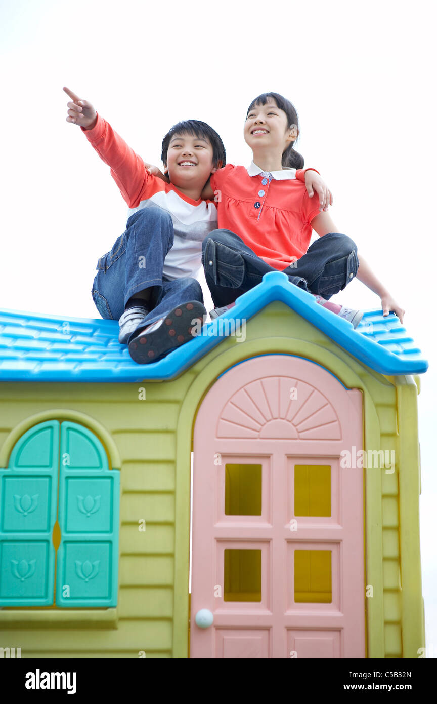 Children sitting on roof of toy house Stock Photo - Alamy