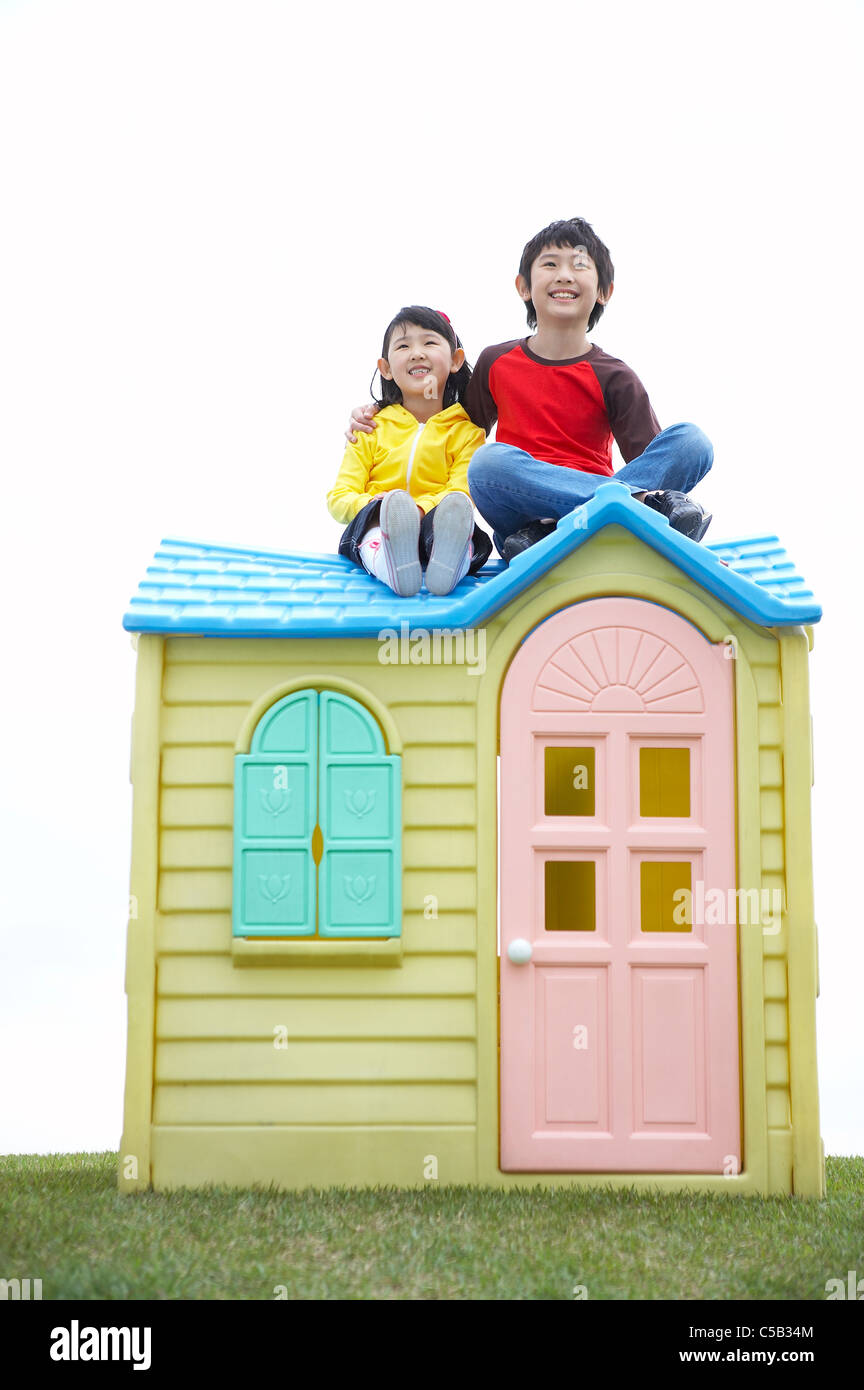 Children sitting on roof of toy house Stock Photo - Alamy