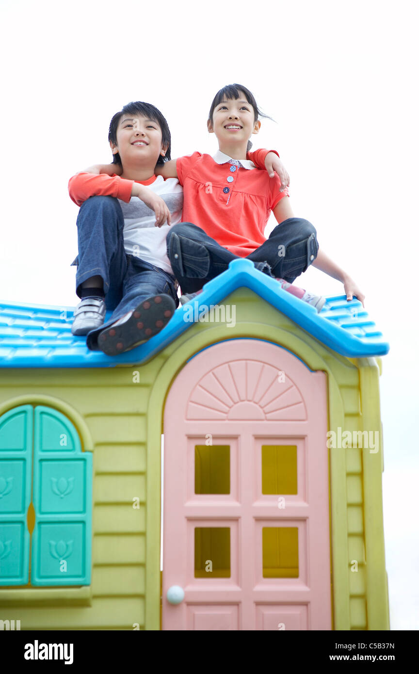 Children sitting on roof of toy house Stock Photo - Alamy