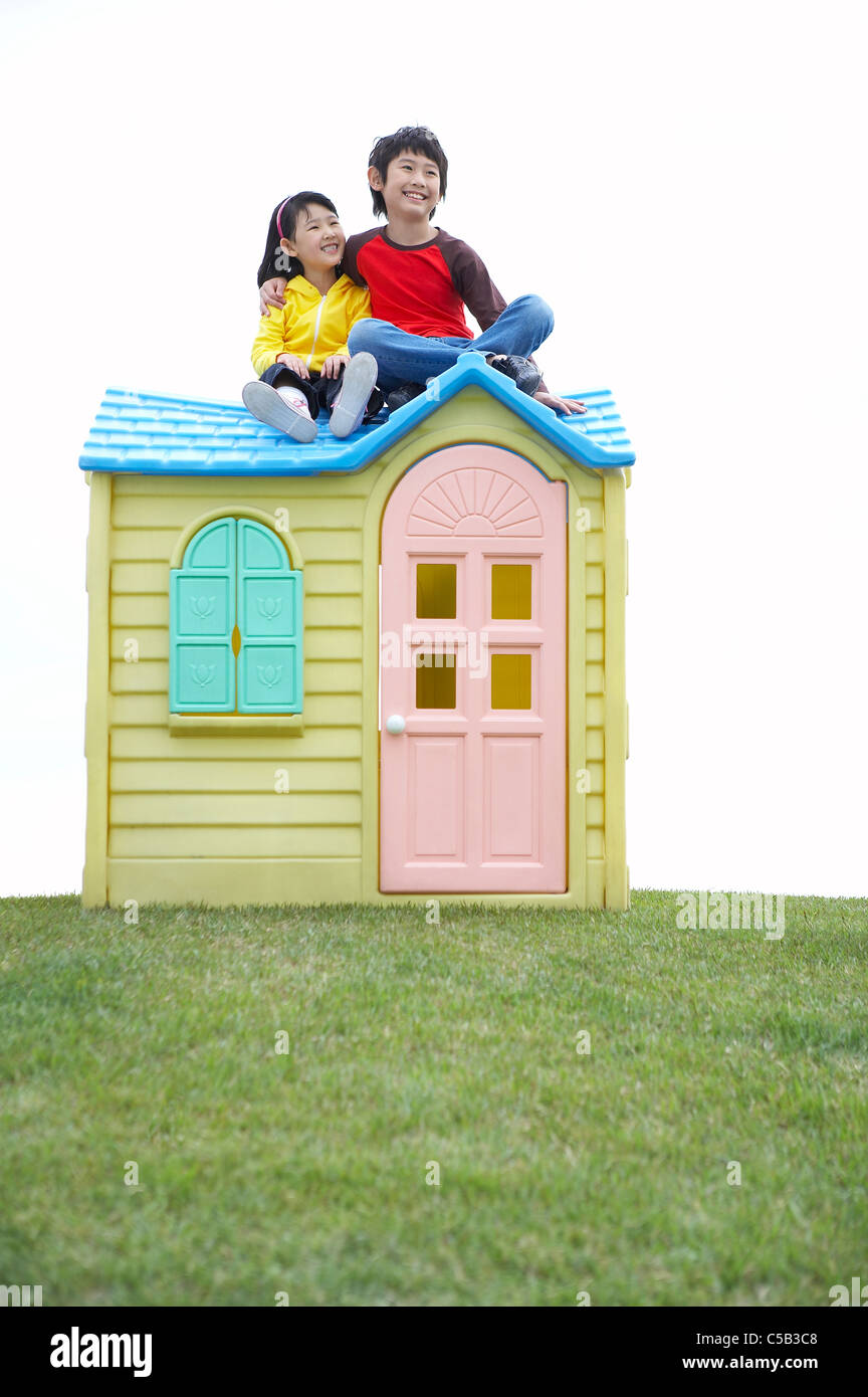 Children sitting on roof of toy house Stock Photo - Alamy