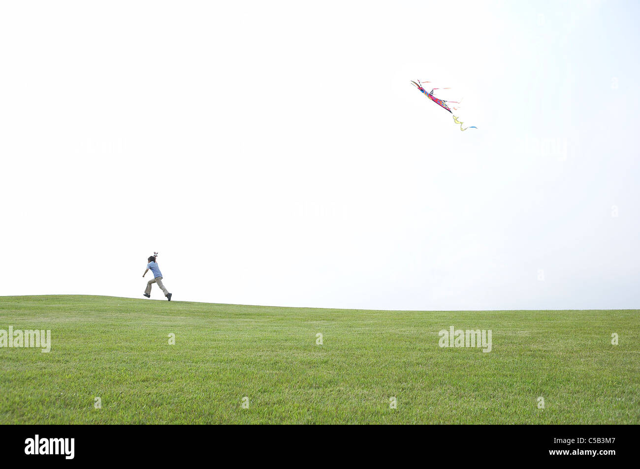 Side view of boy flying kite on lawn Stock Photo - Alamy