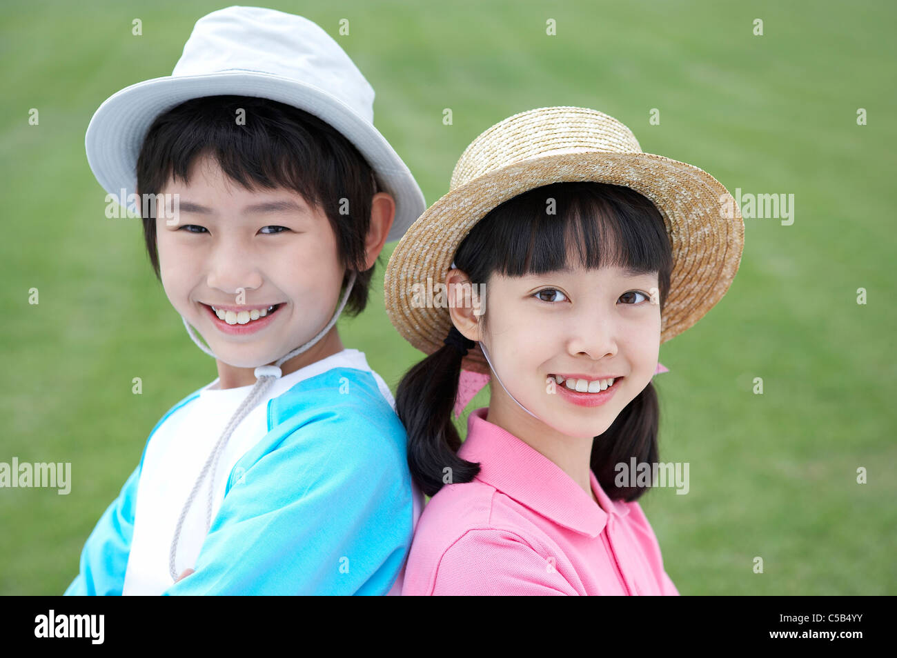 Portrait of children standing back to back in lawn Stock Photo - Alamy