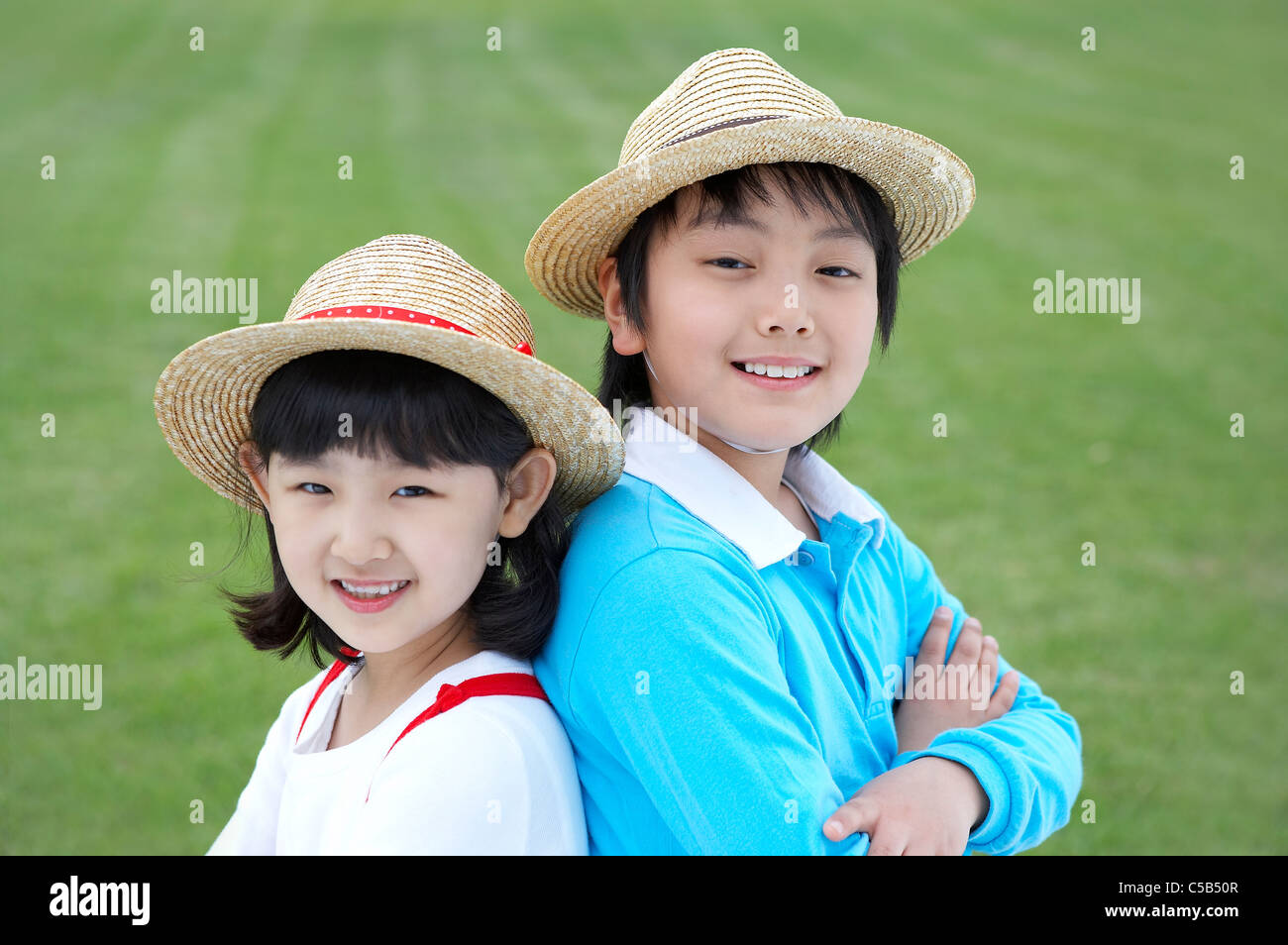 Portrait of children standing back to back in lawn Stock Photo - Alamy
