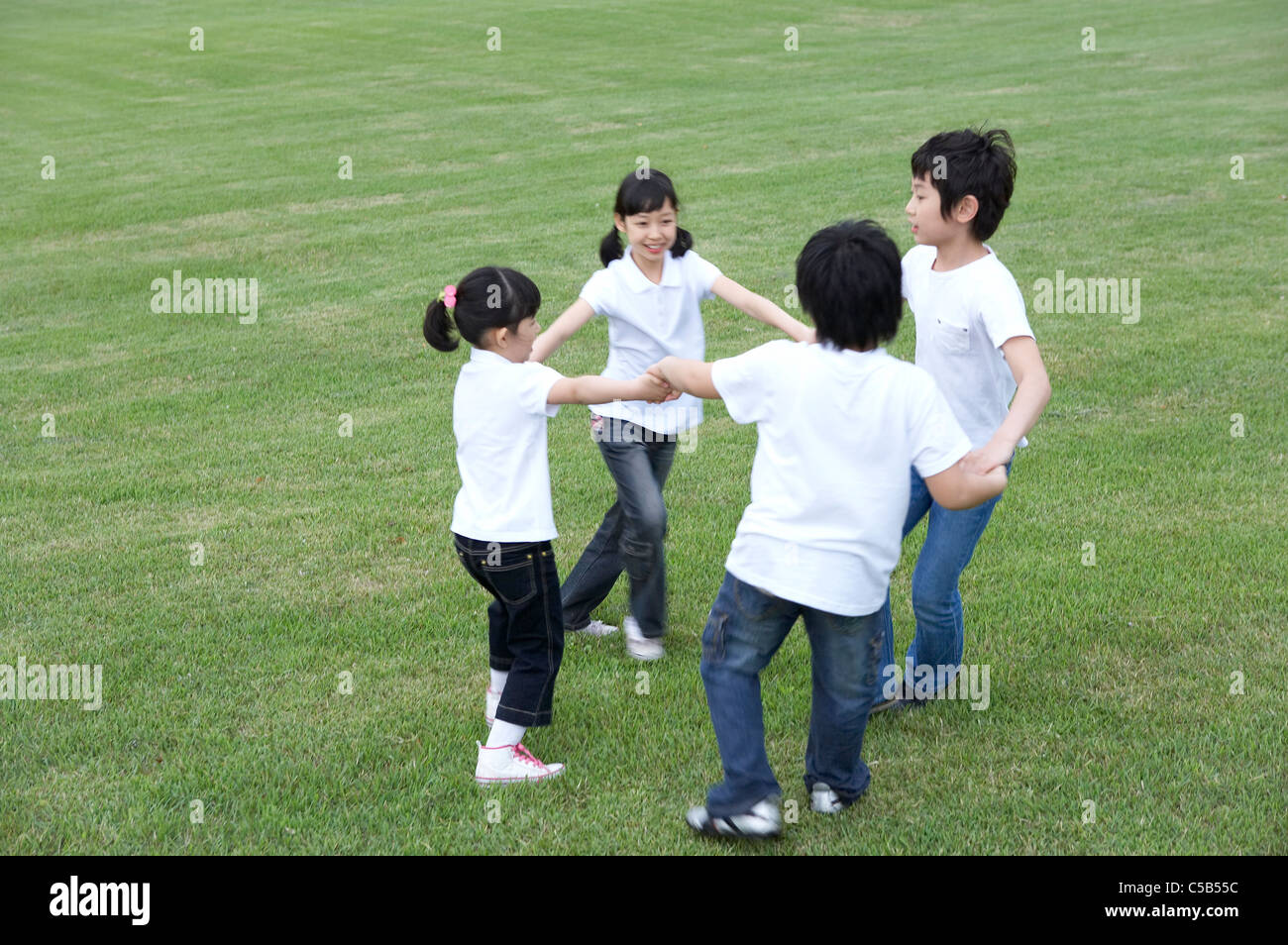 Elevated view of children playing ring-around-the-rosy in lawn Stock ...