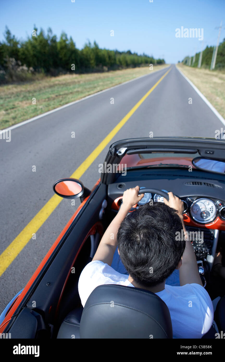 Rear View of young man driving convertible Stock Photo - Alamy