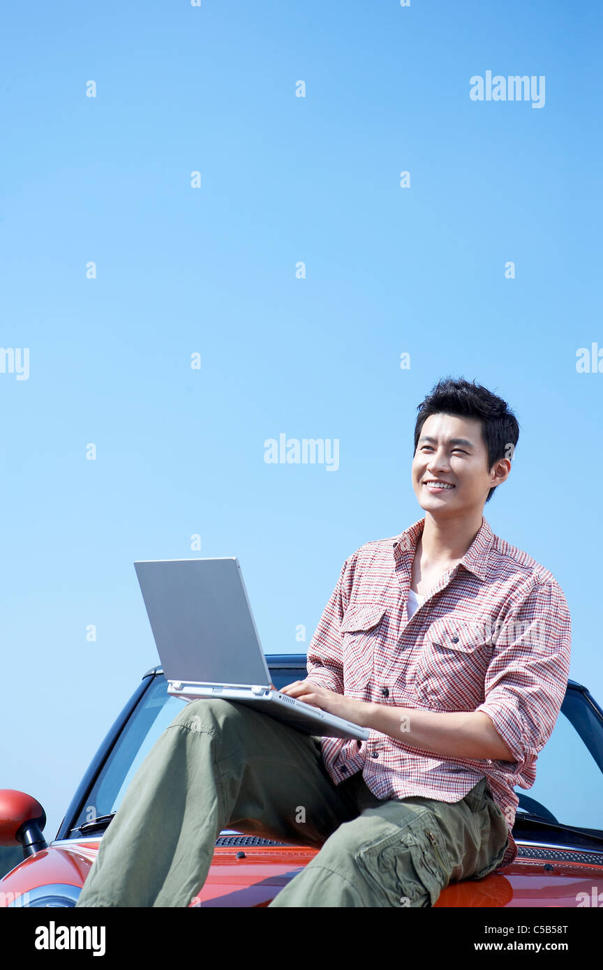 Man sitting on car with laptop Stock Photo - Alamy
