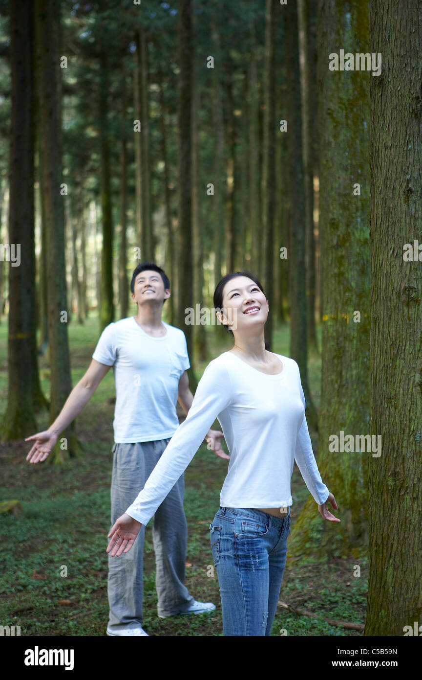 Young couple with arms outstretched in forest Stock Photo - Alamy