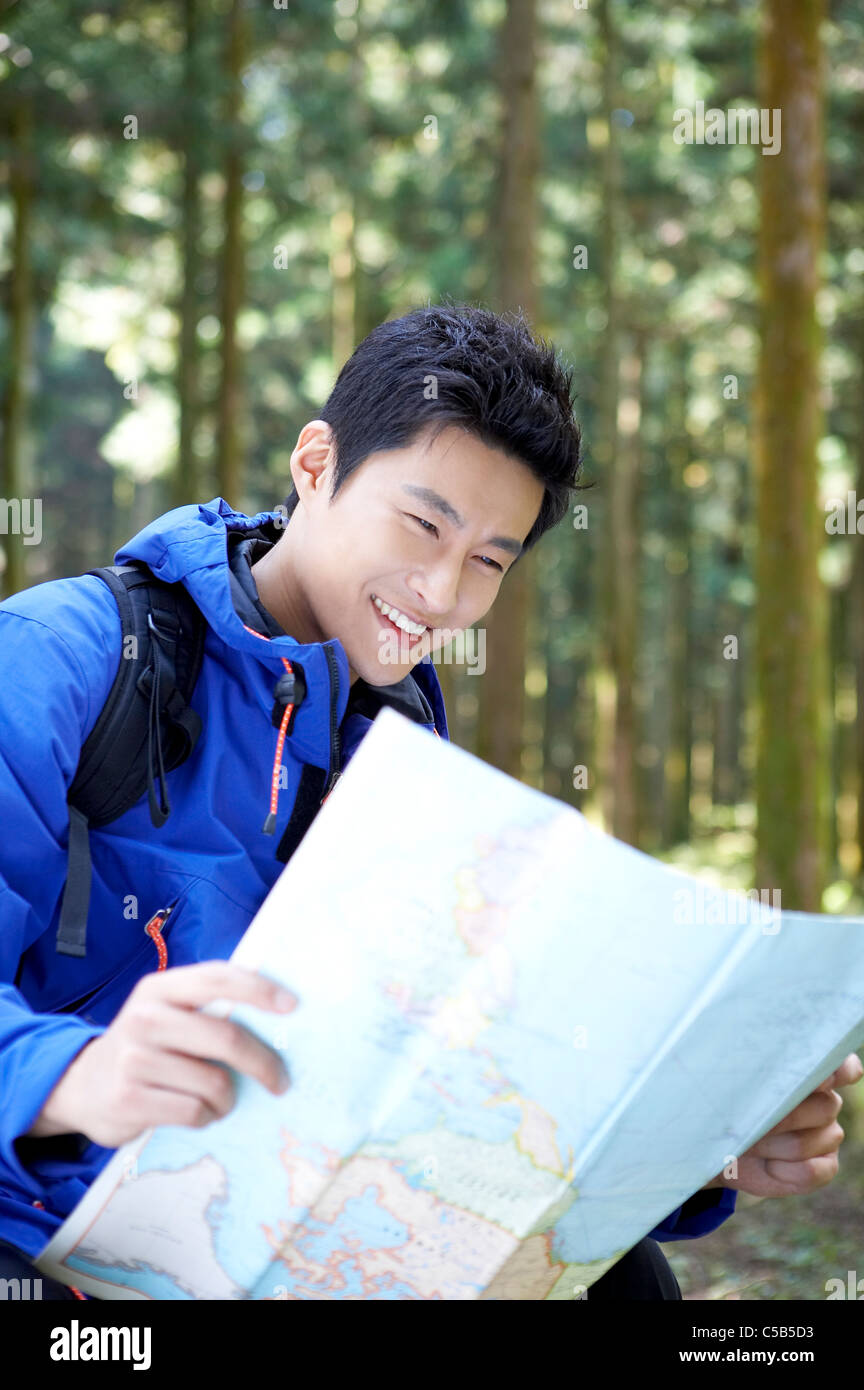 Young man reading map in forest Stock Photo - Alamy