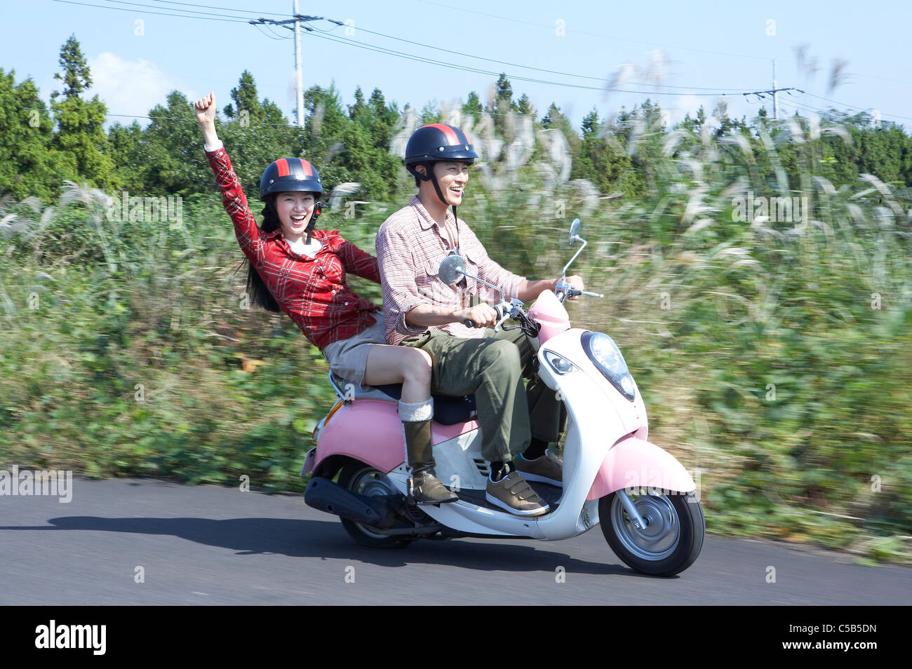 Side view of young couple on Motor Scooter Stock Photo - Alamy