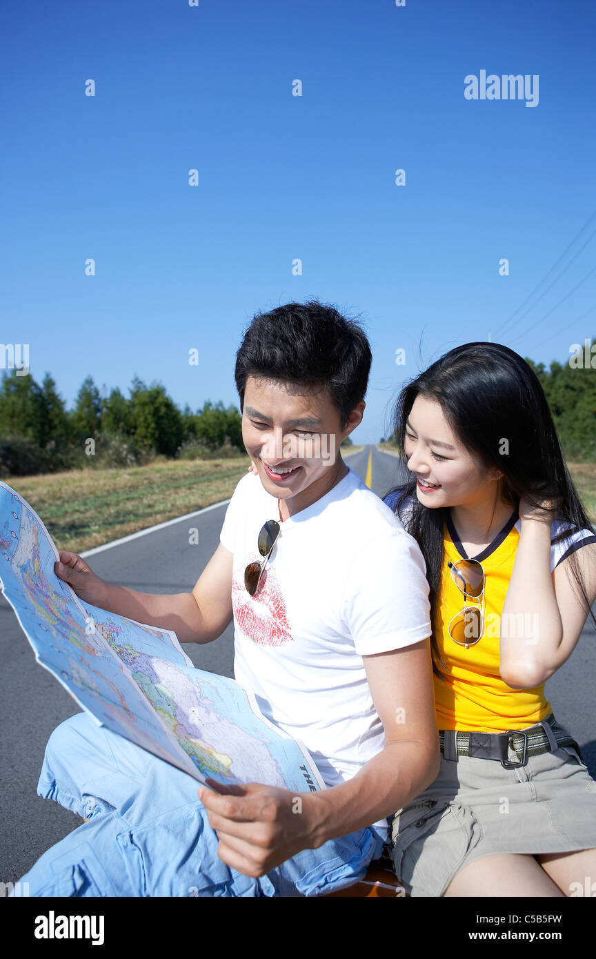 Couple reading map on road Stock Photo - Alamy