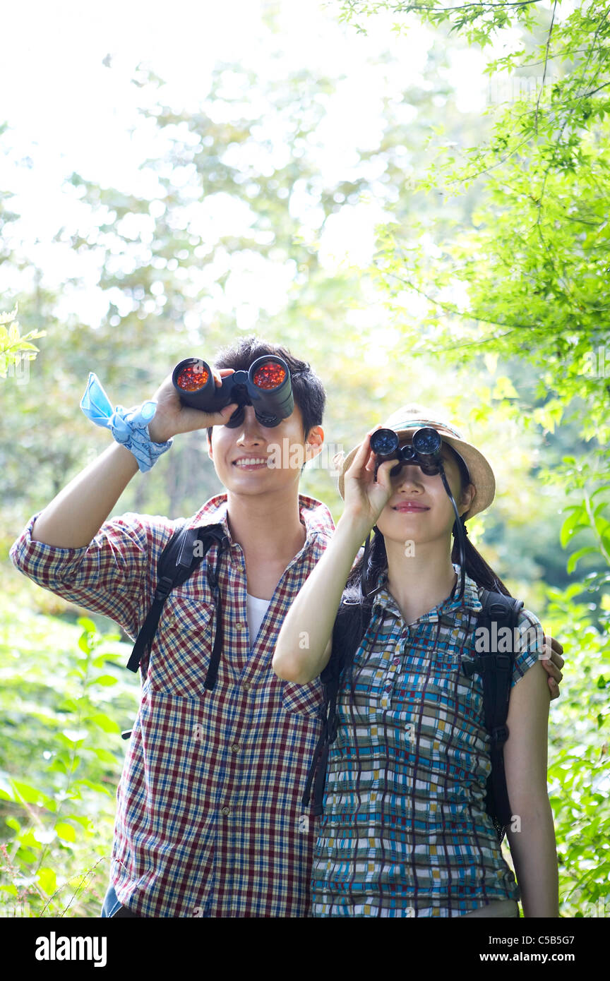 Couple in forest looking through binoculars Stock Photo - Alamy