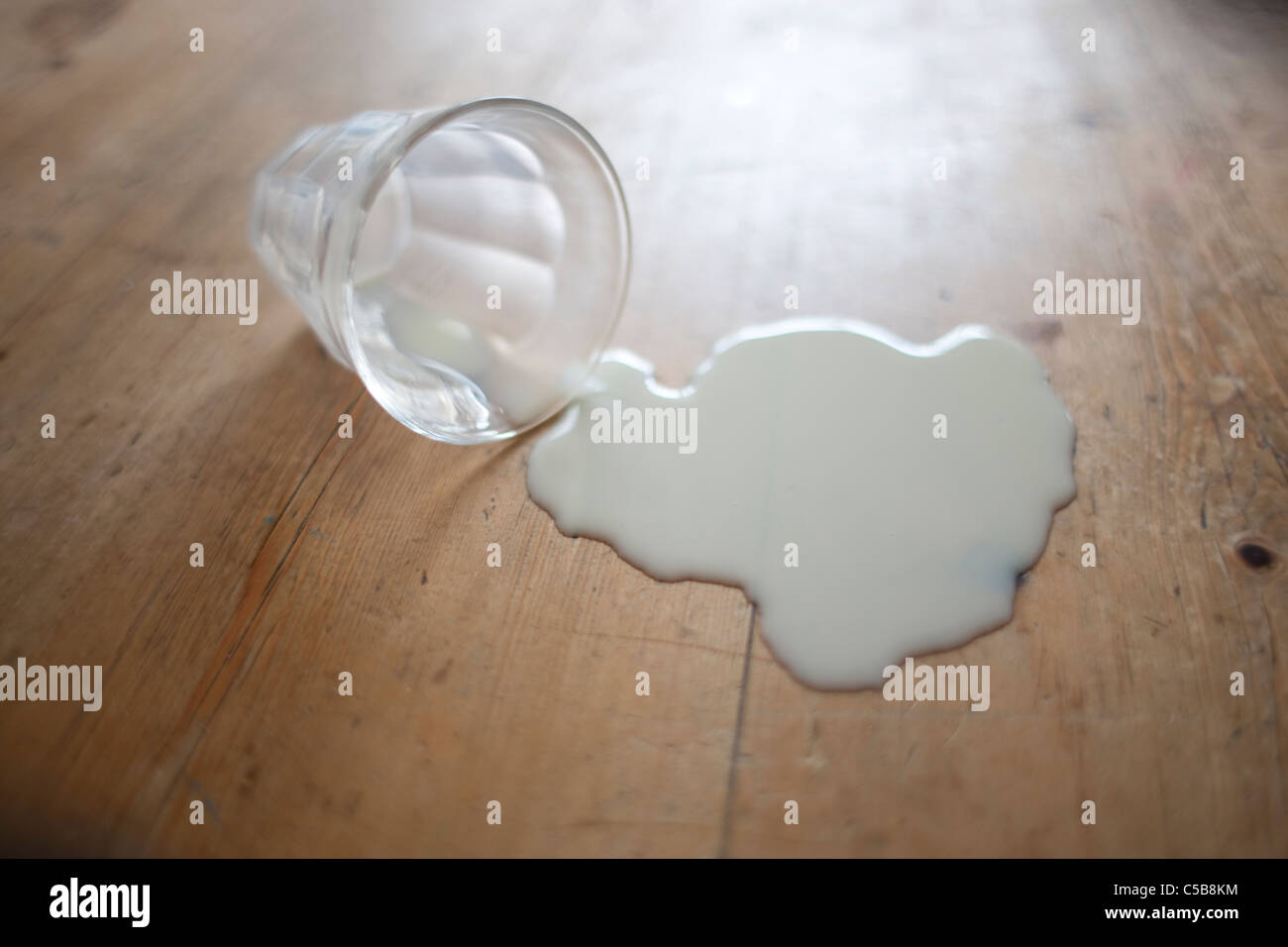 Glass of milk spilt on wooden floor Stock Photo - Alamy