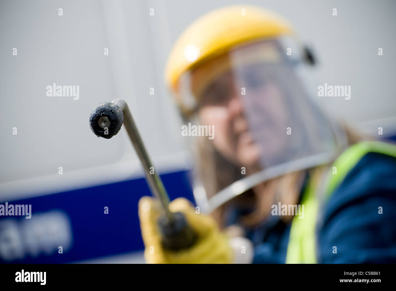 Council worker using a jet wash to clean graffiti off of a wall in ...