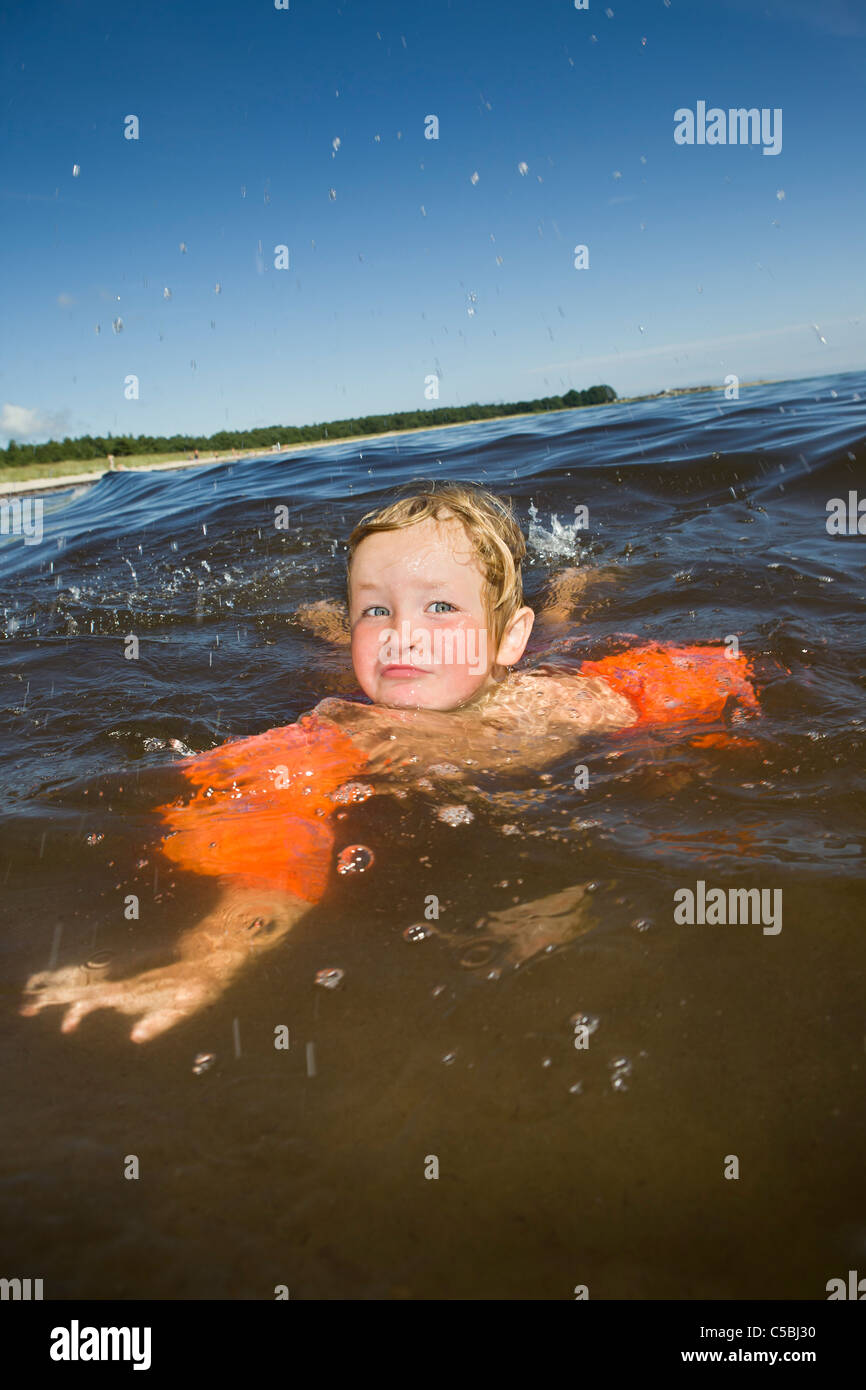 Portrait of a boy swimming with inflated orange water wings Stock Photo ...
