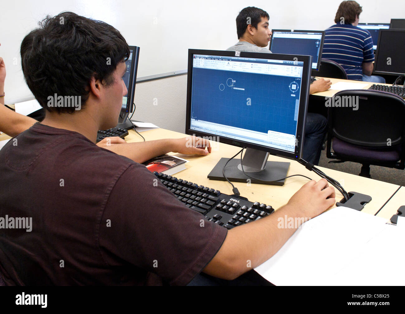 Male student uses computer with flat screen monitor inside computer lab ...