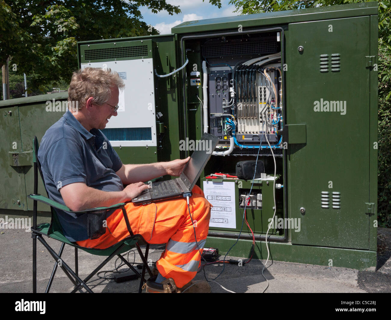 Engineer adding software to Fibre Optics Broadband Network Junction Box ...