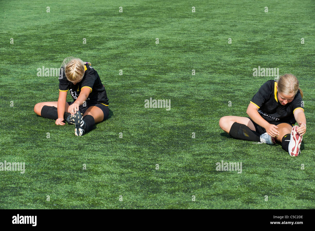 Two girls stretching on the grass at lawn Stock Photo - Alamy