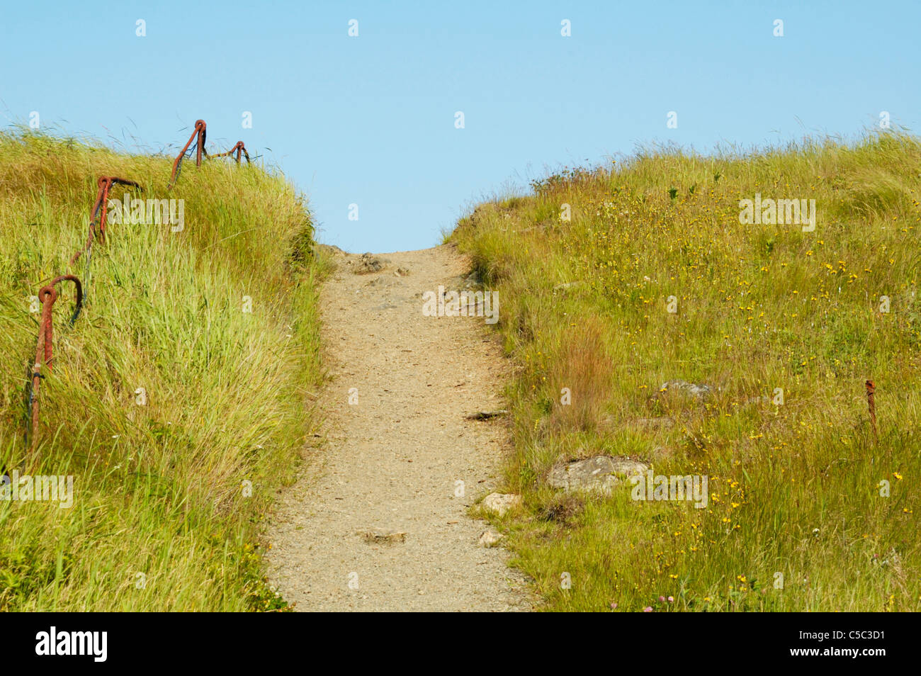 A pathway going up a hill with an old wire railing alongside Stock ...