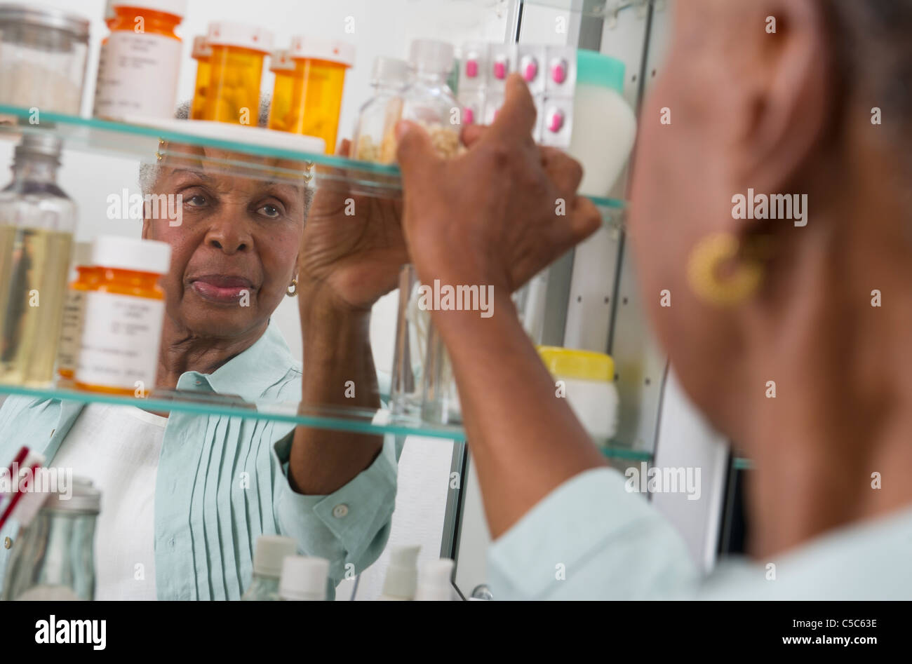Black woman taking medication from cabinet Stock Photo - Alamy
