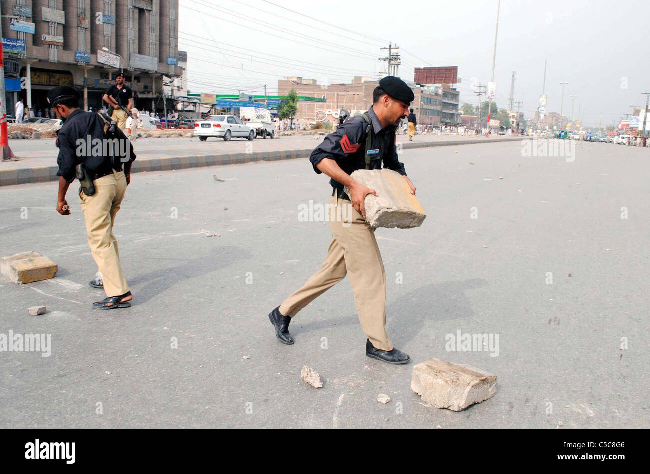 Policemen remove stones which were pelted by angry protestors during ...