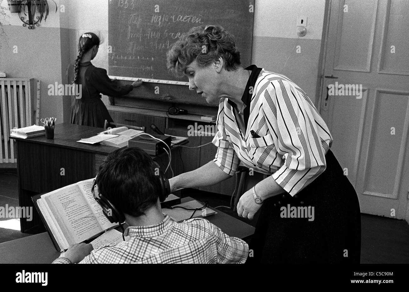 A female teacher in the classroom teaching, with the aid of a ...